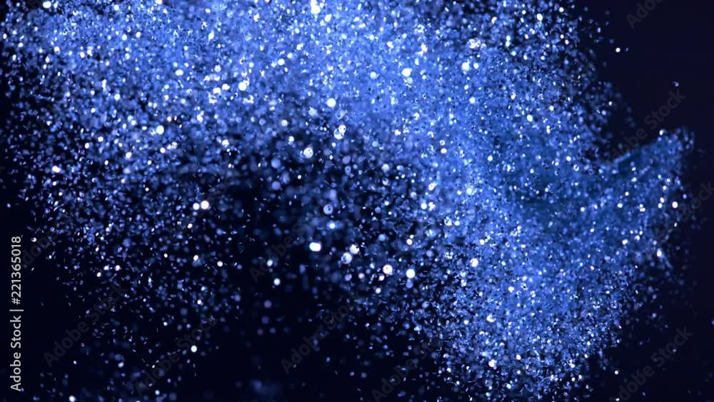 Super slow motion of glittering blue particles on black background ...