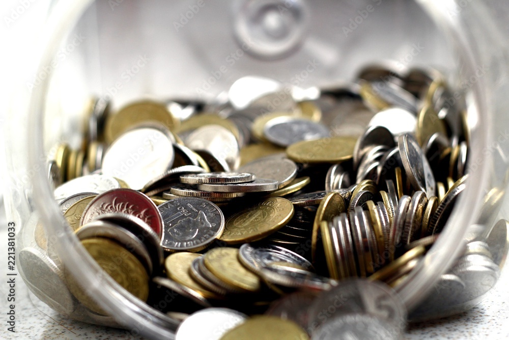 Coins spilling out of a coin bank or container Stock Photo | Adobe Stock
