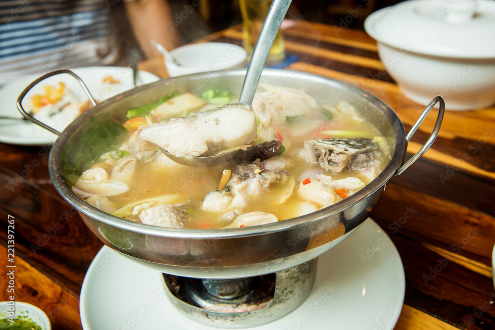 Thai spicy freshwater fish soup with herbs, served in big bowl. Tom Yam ...