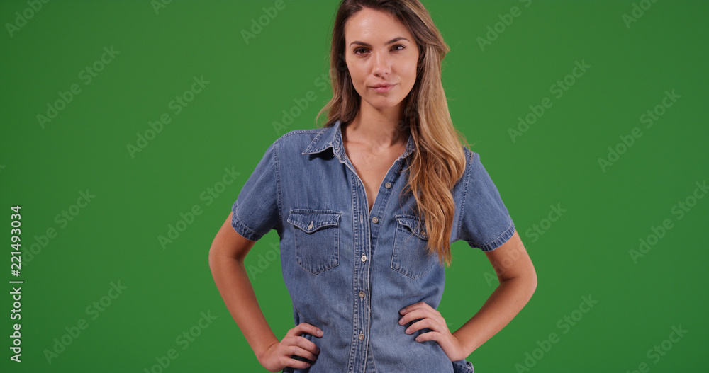 Attractive female millennial standing with hands at her hips on green ...