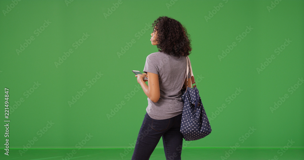 Rear view of black woman texting on smartphone on green screen Stock ...