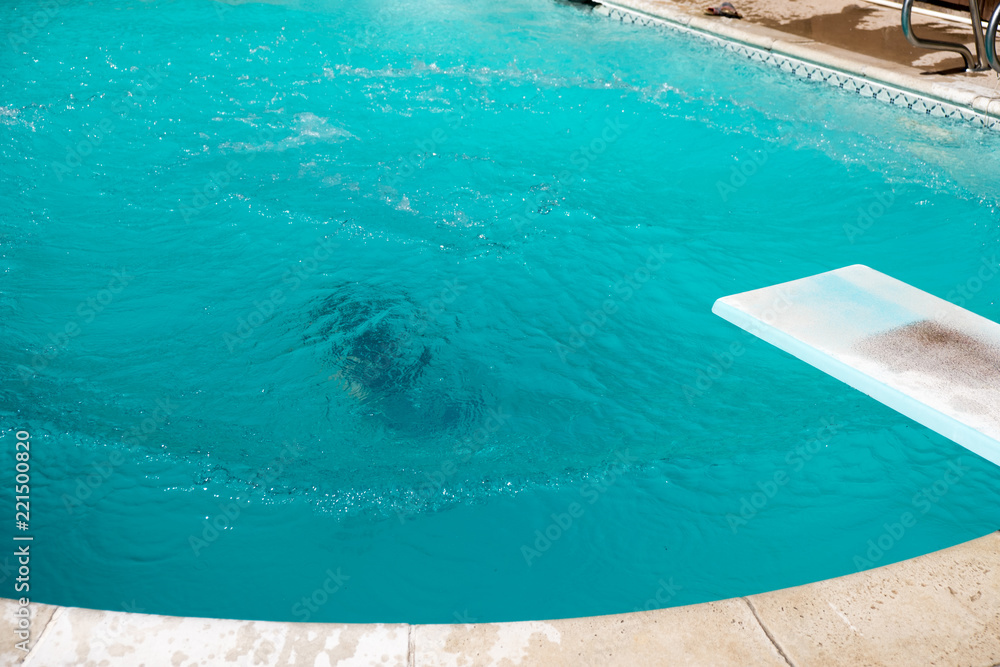 Woman underwater after jumping into a swimming pool from diving board ...