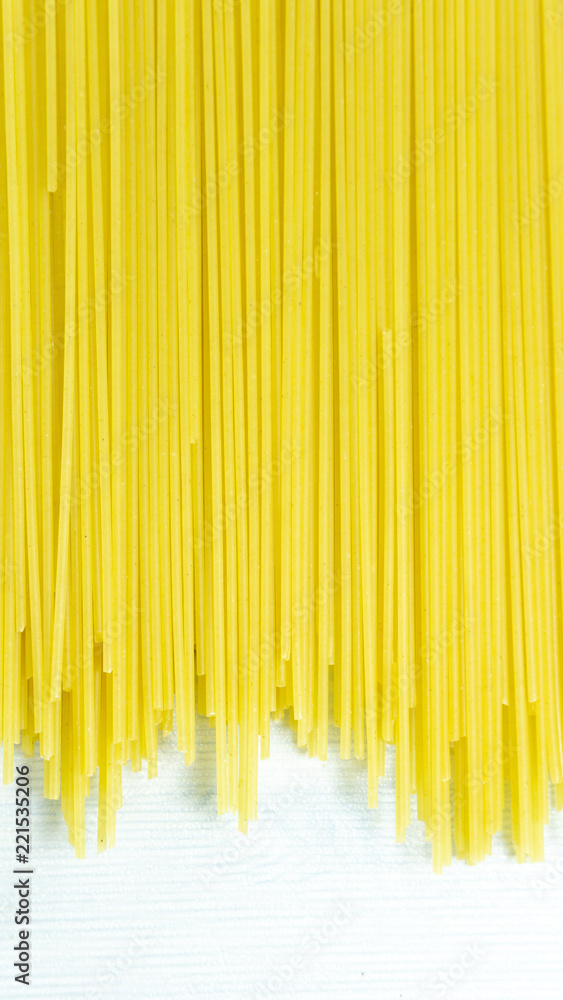 Yellow long spaghetti on black background. Thin pasta arranged in rows ...