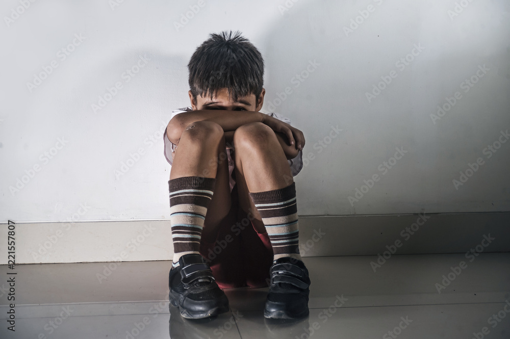 young sad and scared hispanic kid 8 years old in school uniform sitting ...