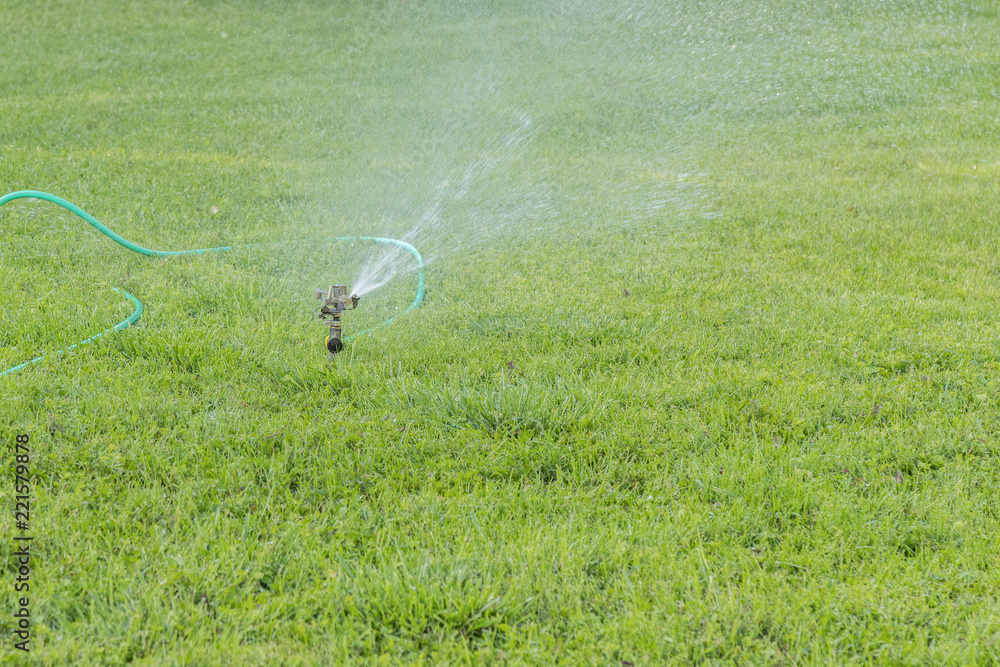Lawn sprinkler spaying water over green grass. Irrigation system ...