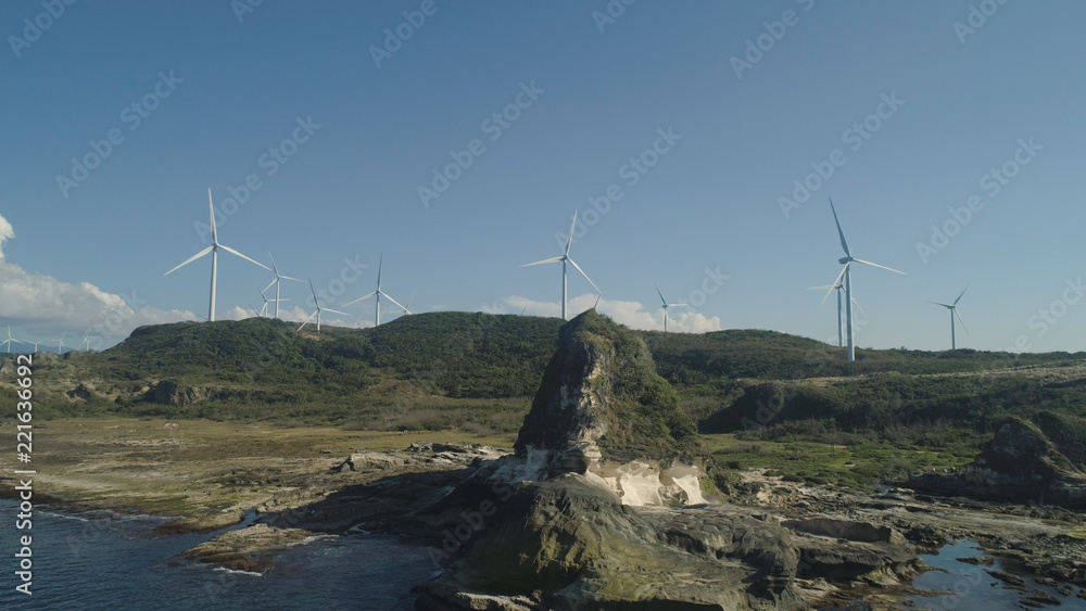 Natural rock formation of limestone stone on the coast with windmills ...