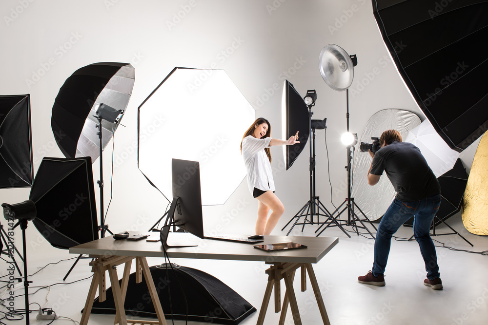 Photographer and pretty model working in modern lighting studio with ...