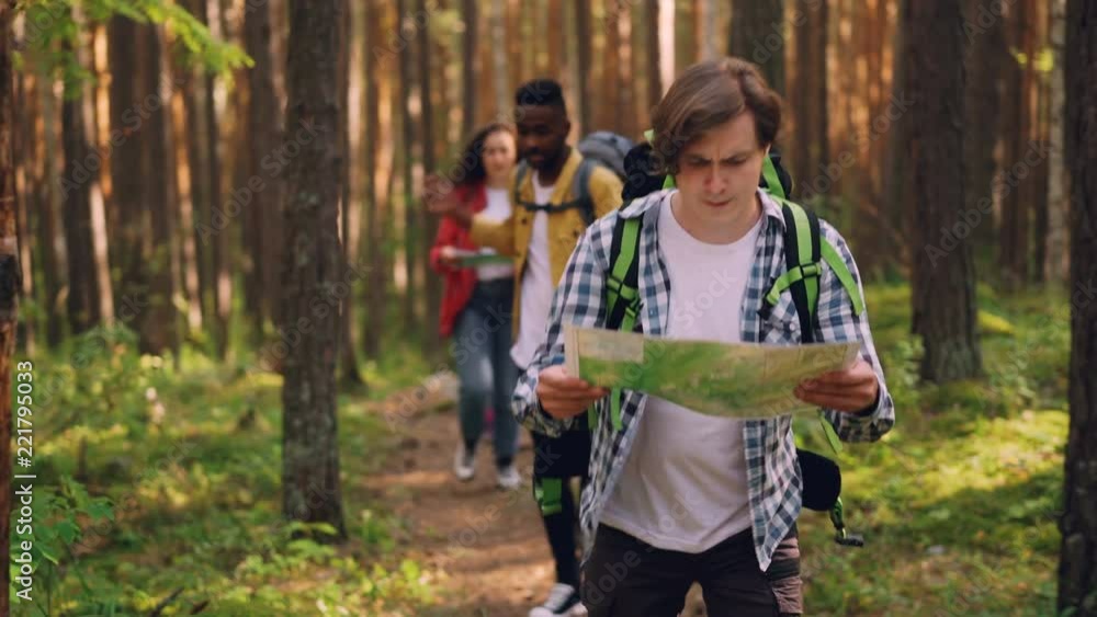Smiling young man is looking at map and searching for right way in ...
