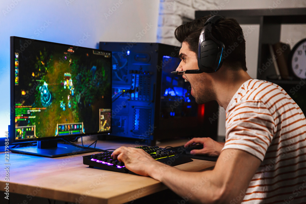 Portrait of angry gamer guy wearing headset yelling, while playing ...