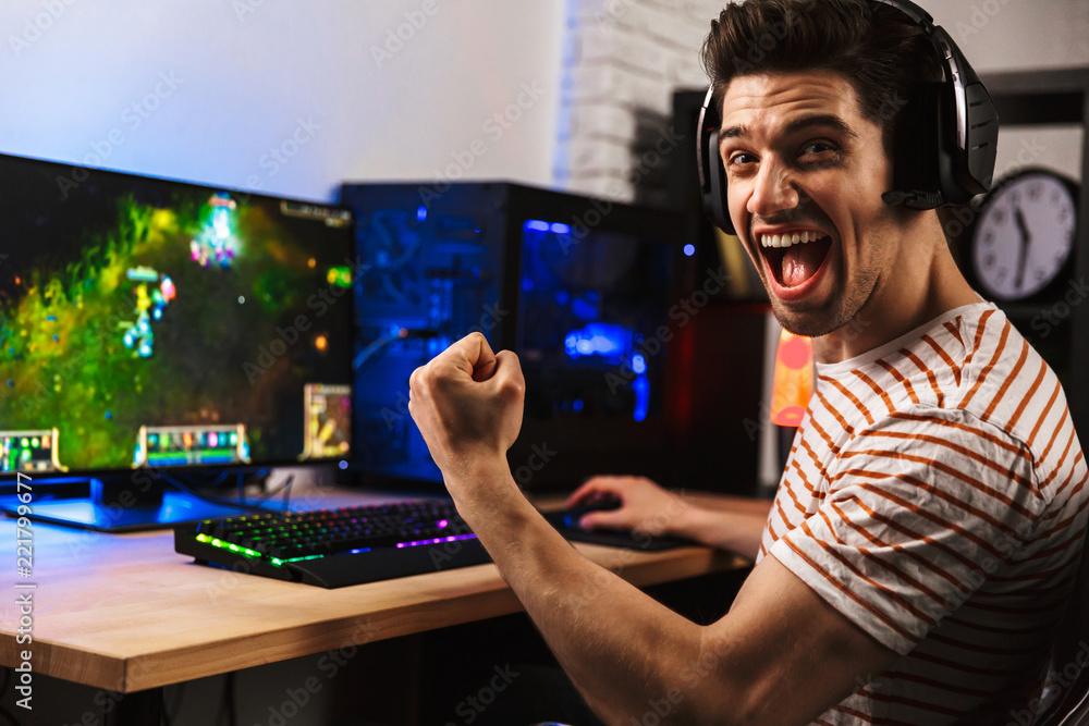 Portrait of ecstatic gamer guy in headphones screaming and rejoicing ...