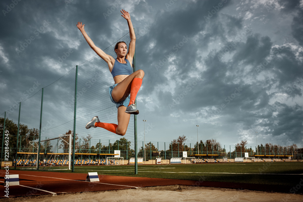 Female athlete performing a long jump during a competition at stadium ...