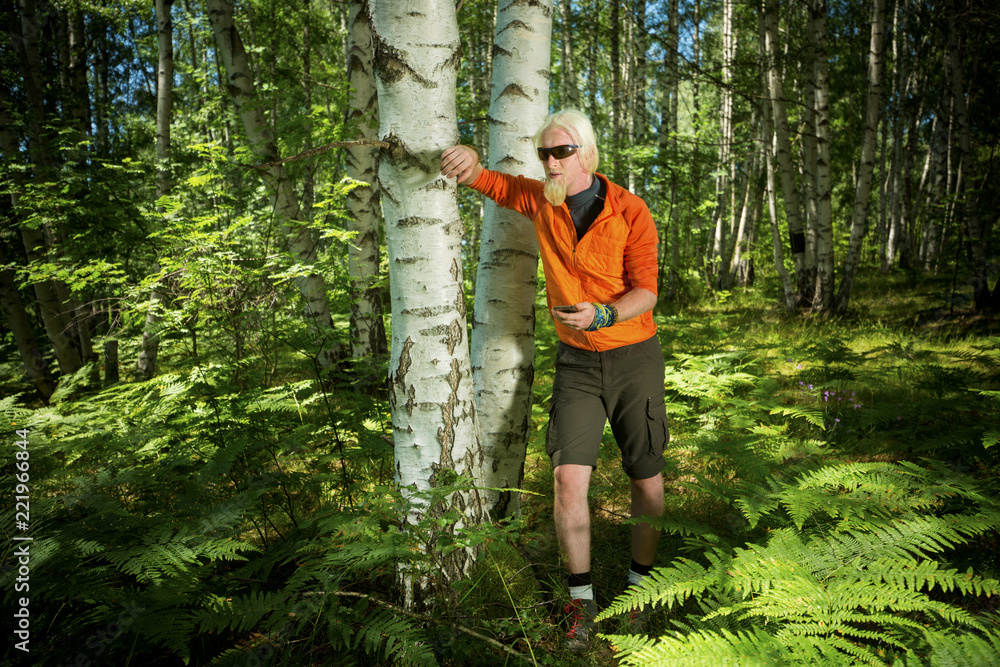 Men with a long blonde hair and beard leaning on a tree in forest Stock ...