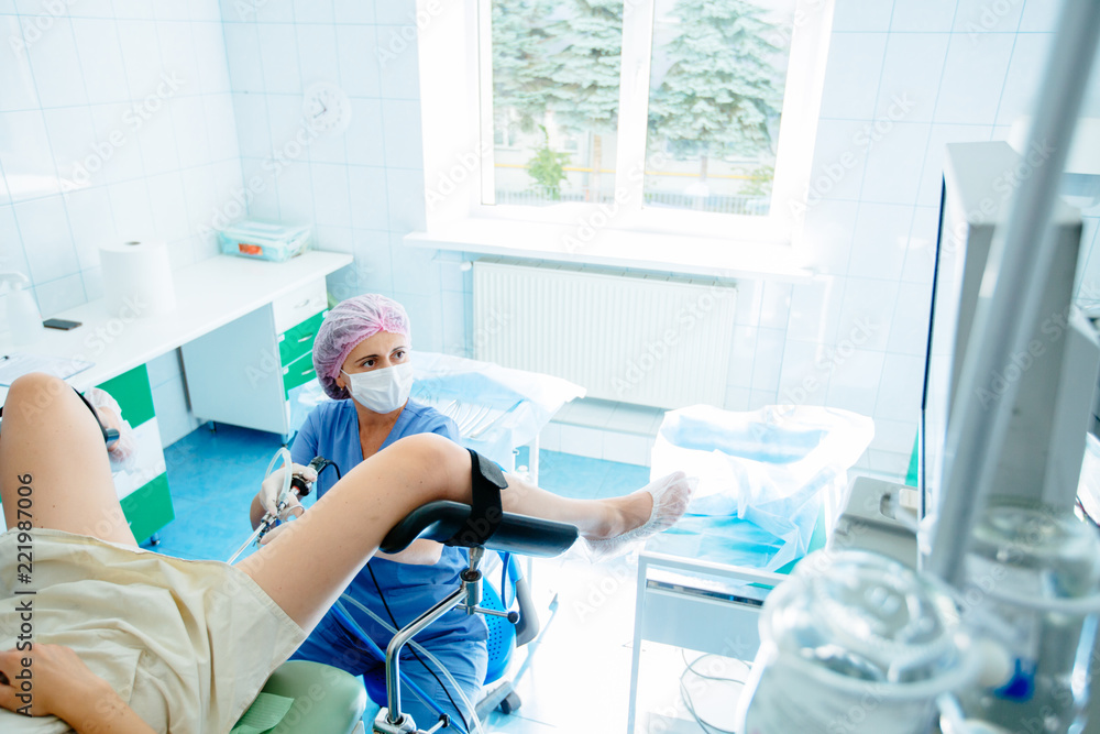 Female gynecologist in mask and hair cap with unrecognizable patient in ...