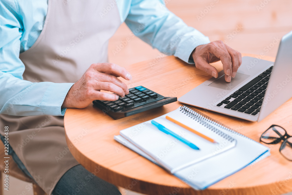 Daily calculation. Professional businessman using calculator while ...