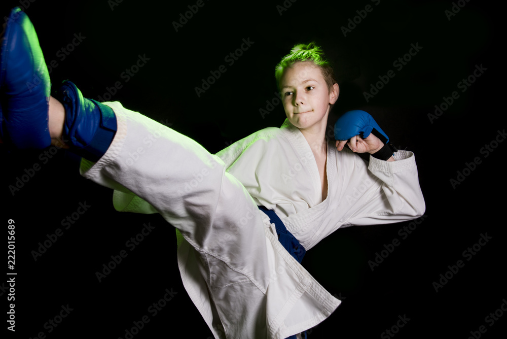 Young boy training karate on black background. Blue belt and mitts ...
