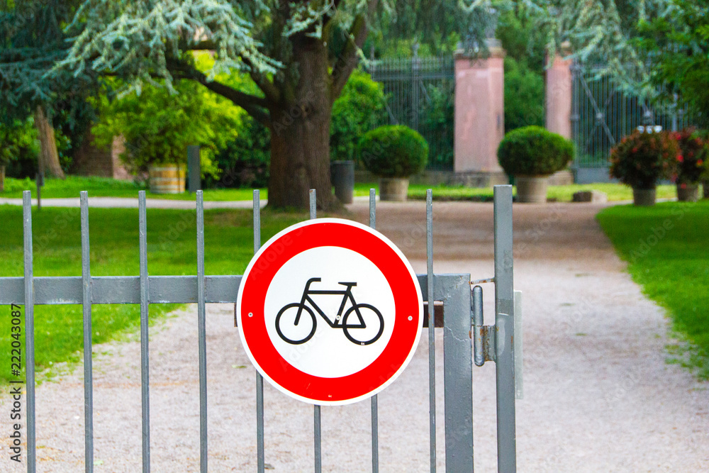 Road sign at the entry of a public park with a fence, where no bikes ...
