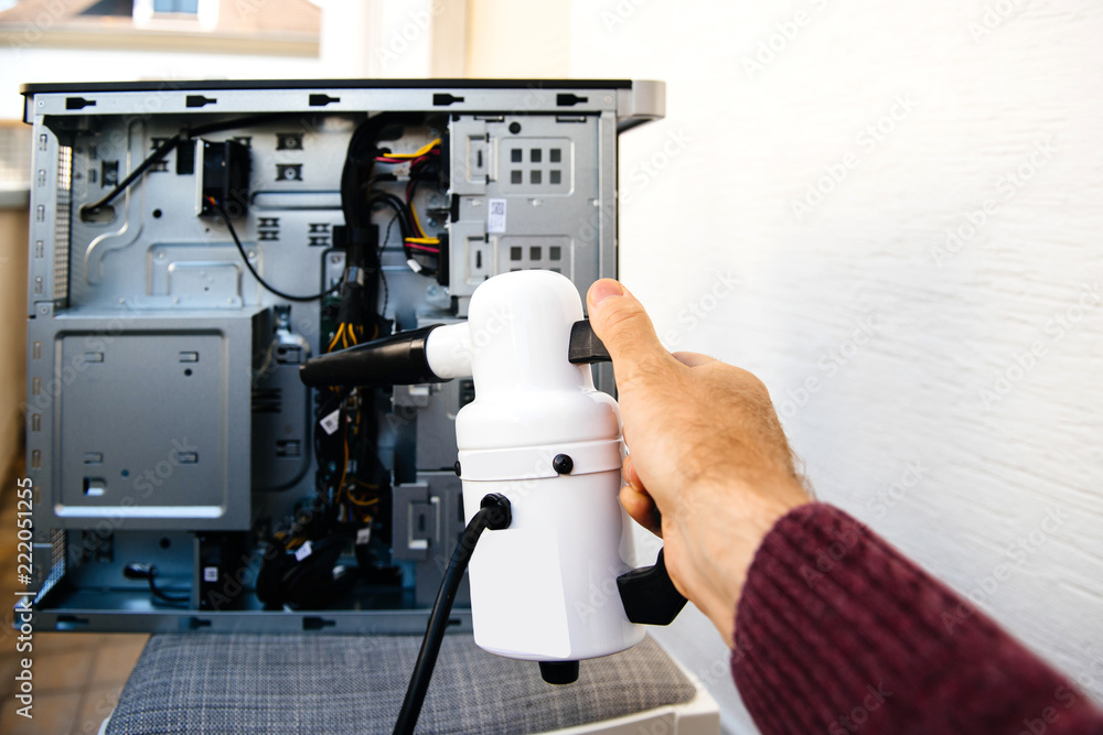 IT guy holding holding vacuum pump to clean computer case on balcony ...
