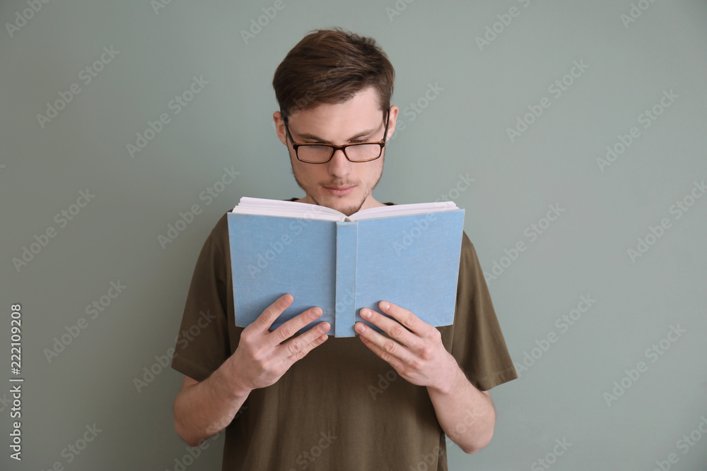 Young man reading book on color background Stock Photo | Adobe Stock