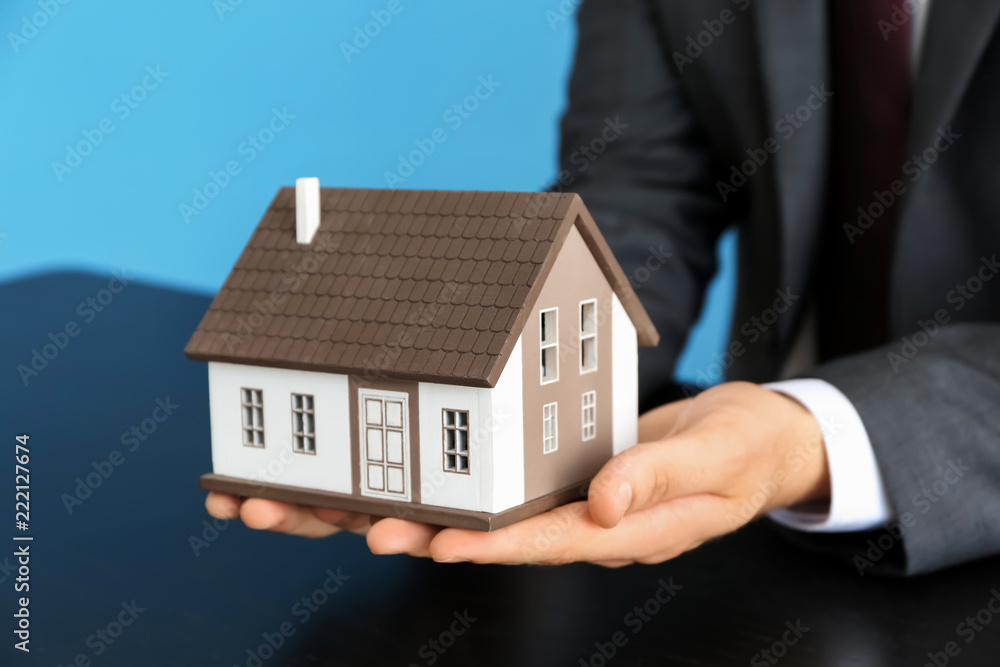 Real estate agent with house model at dark table. Mortgage concept ...