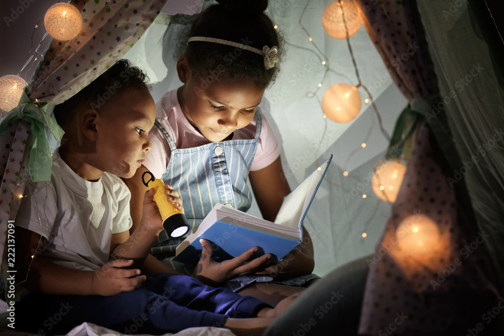 Little African-American children reading bedtime story in hovel Stock ...