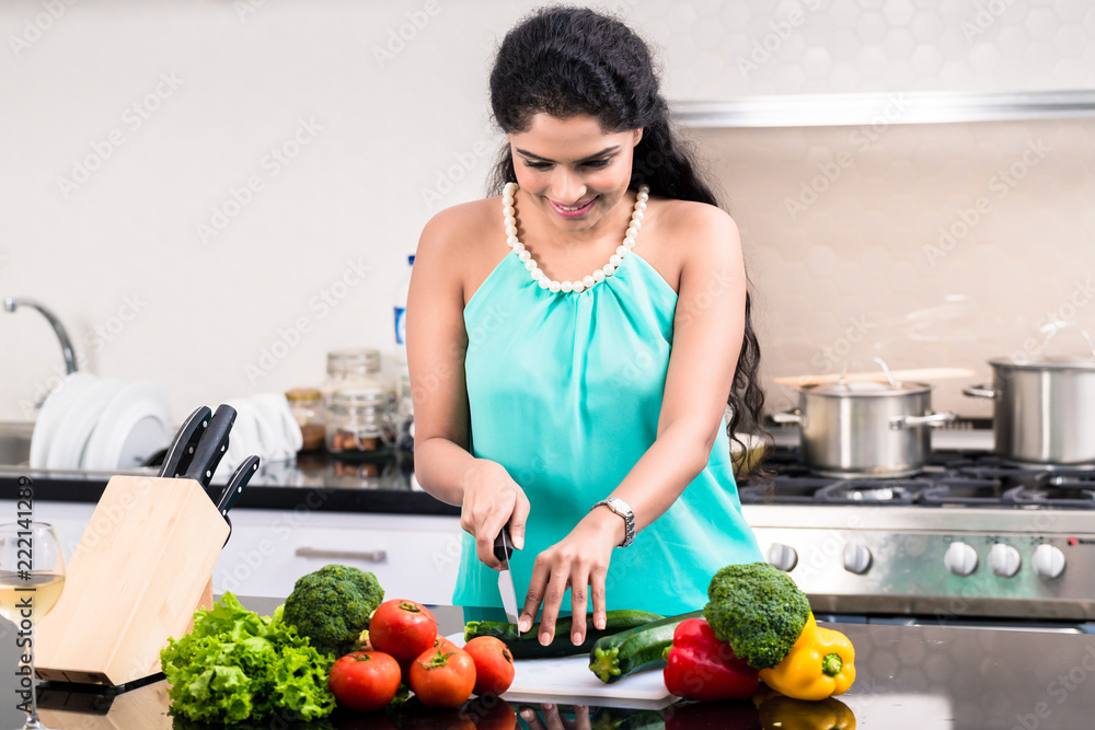 Smiling beautiful woman chopping vegetables with knife in kitchen Stock ...