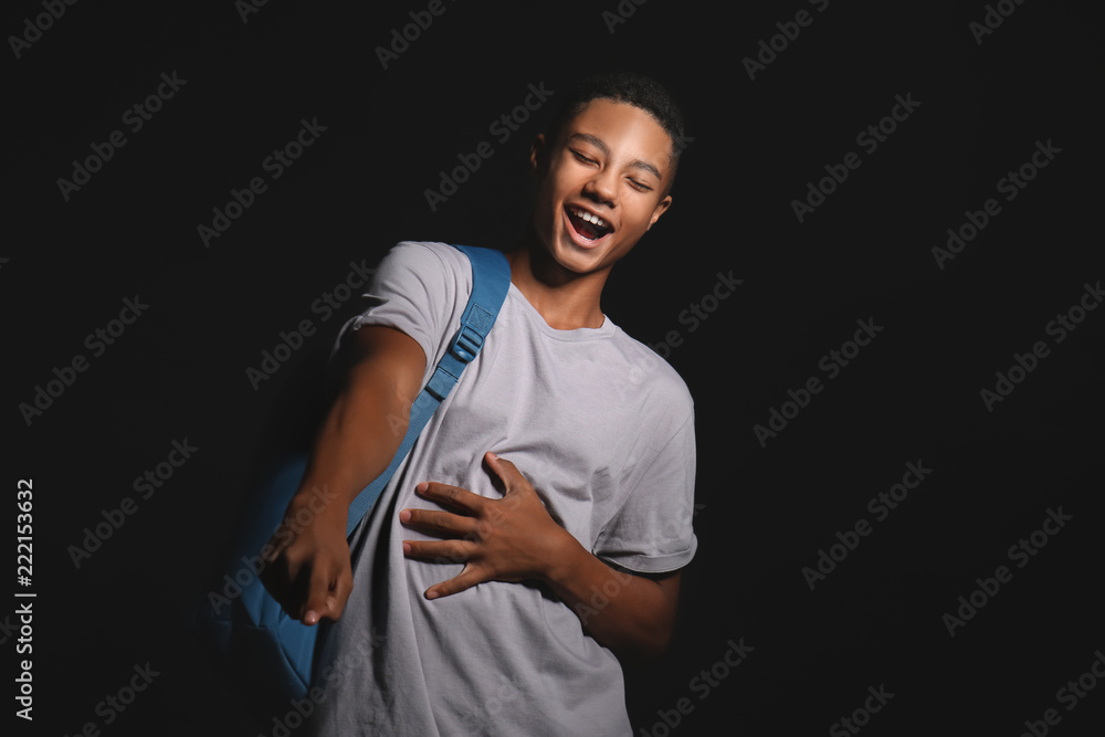 Laughing bully African-American teenage boy laughing on dark background ...