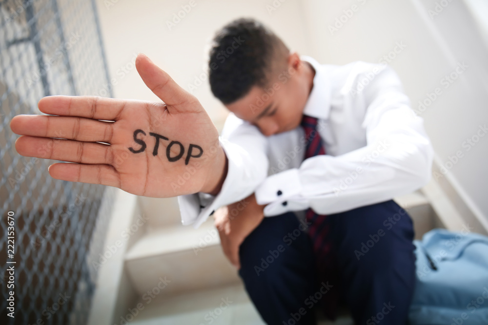African-American teenage boy with word STOP written on hand sitting on ...