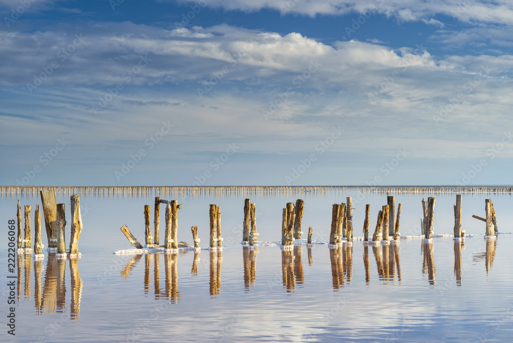 wooden columns under sky with clouds on the red salt lake in Ukraine ...