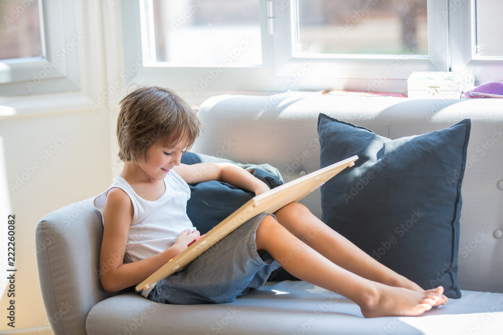 Prechool child, reading a book and playing with wooden educational toy ...
