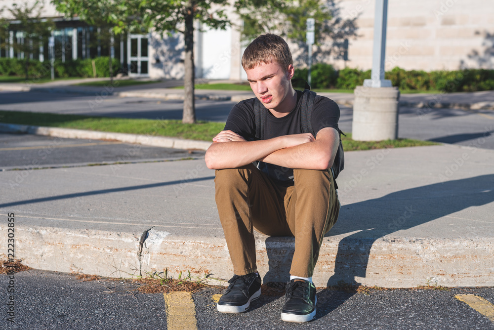 Sad teenage boy sitting on the curb in front of his school. Photos ...