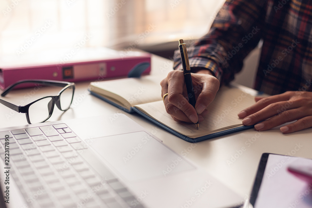 The man is writing a message in the book on table. He is now sitting ...
