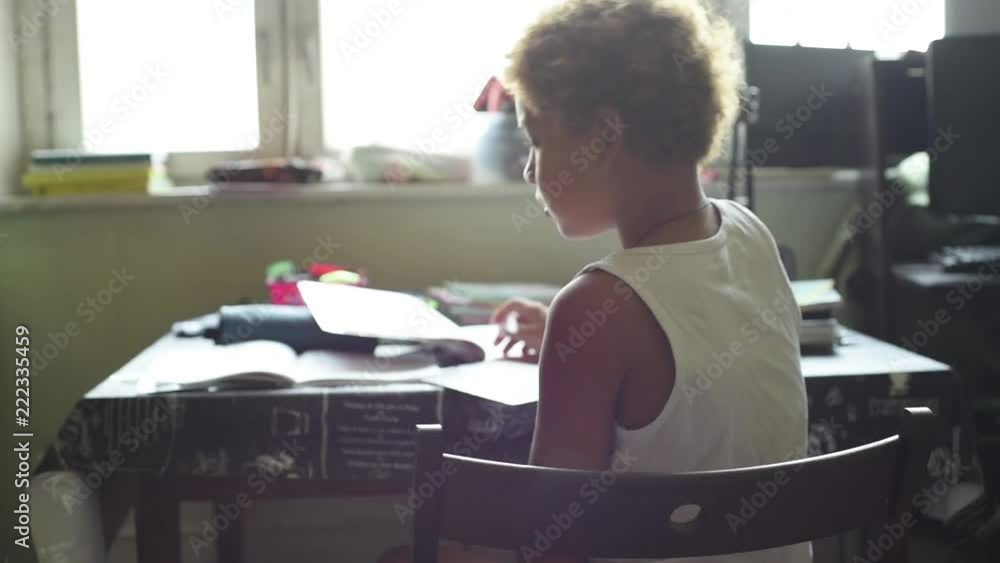 Schoolboy doing homework in his room in the home. Cute african american ...