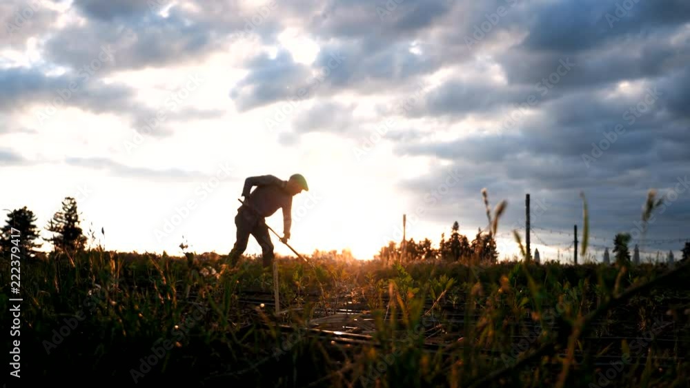 Handsome, rugged farmer on an organic farm, tills the soil during magic ...