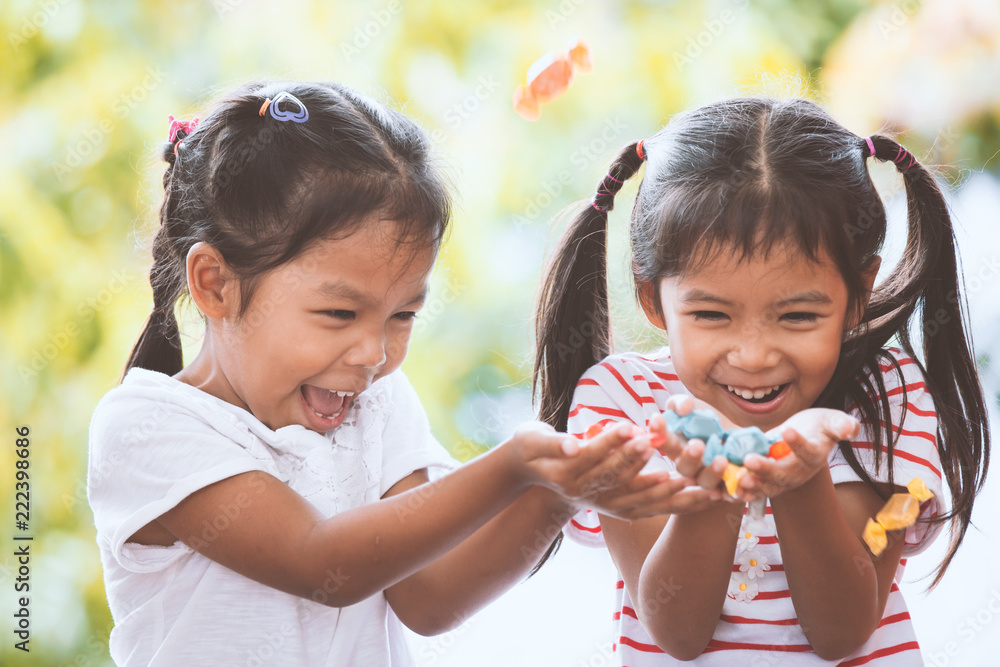Two asian child girls having fun to catching candies falling from the ...
