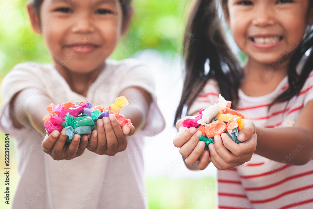 Two asian child girls holding sweet candies in thier hands and share to ...