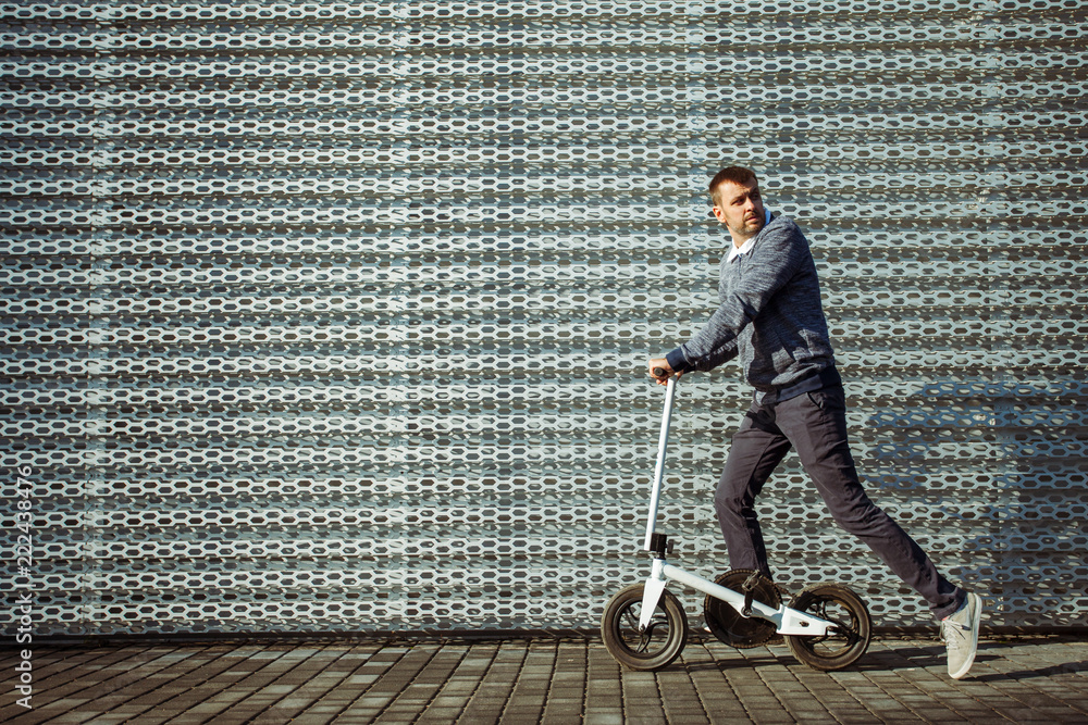 Side view of man pushing kick scooter while riding on beautiful ...