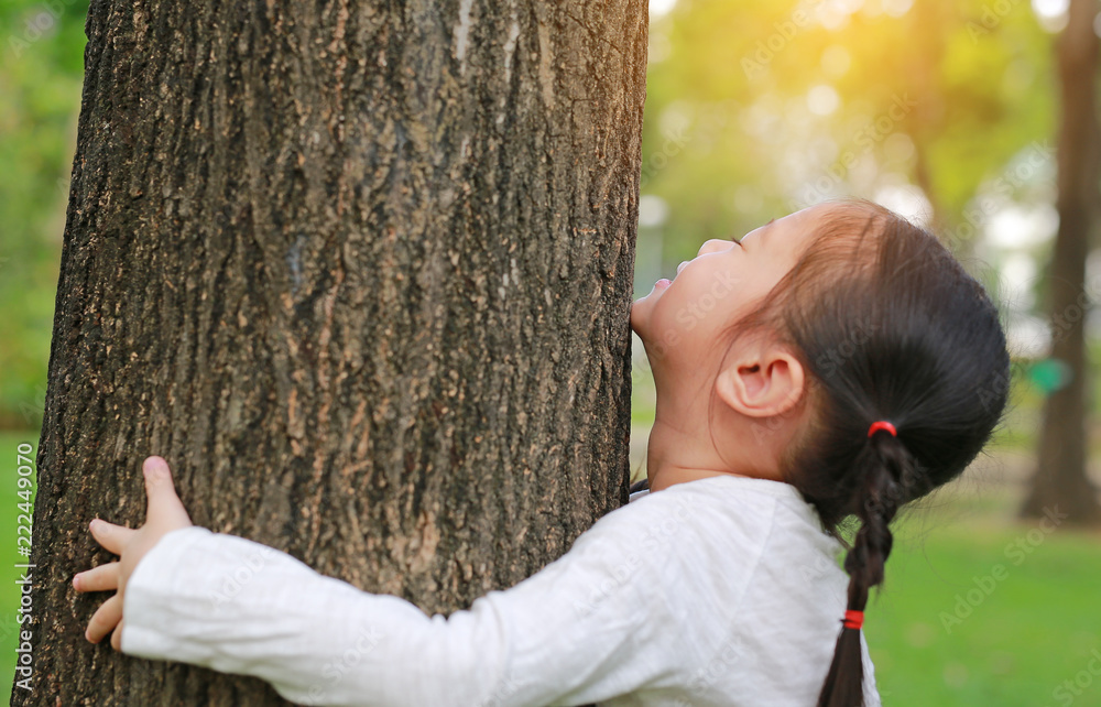 Portrait of cute little child girl and nature. Kid hugging a tree ...