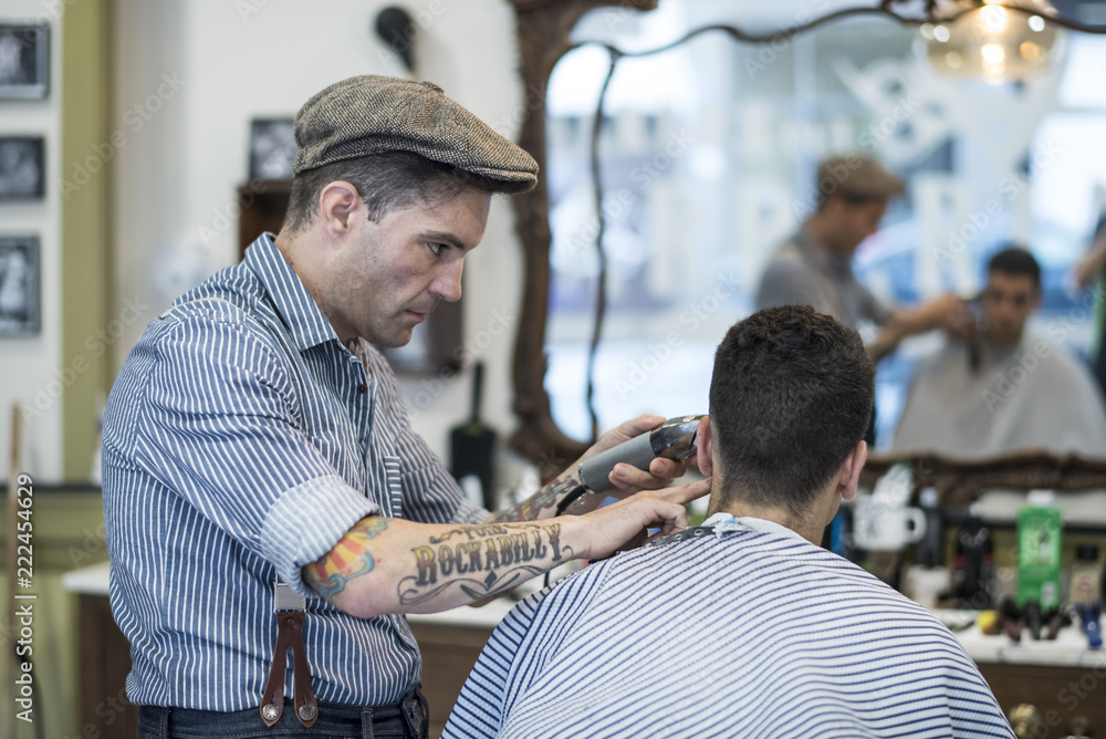 Barbero moderno con vestimenta vintage corta el pelo a joven muchacho ...