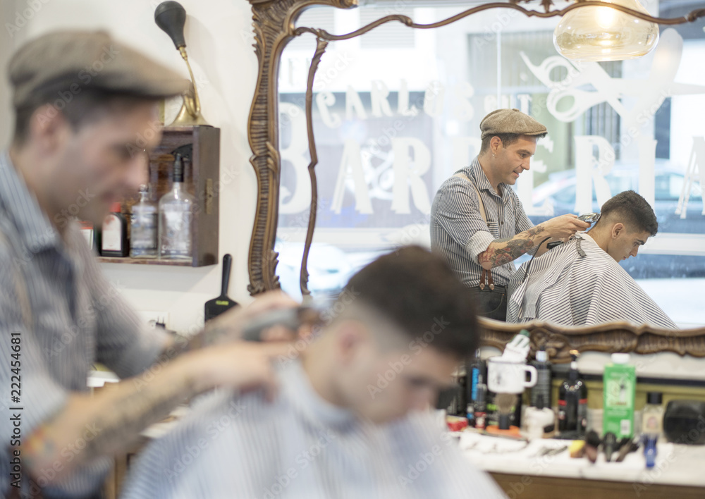 Barbero moderno con vestimenta vintage corta el pelo a joven muchacho ...