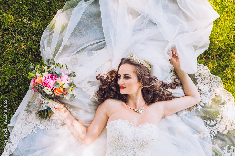 Wedding day of newlyweds. The bride lying on the grass. Beautiful bride ...