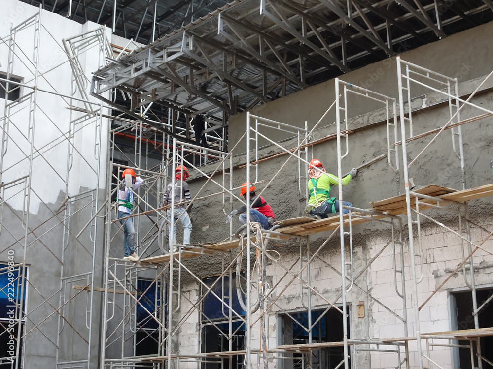 Brick wall plastered by construction workers using the cement plaster ...
