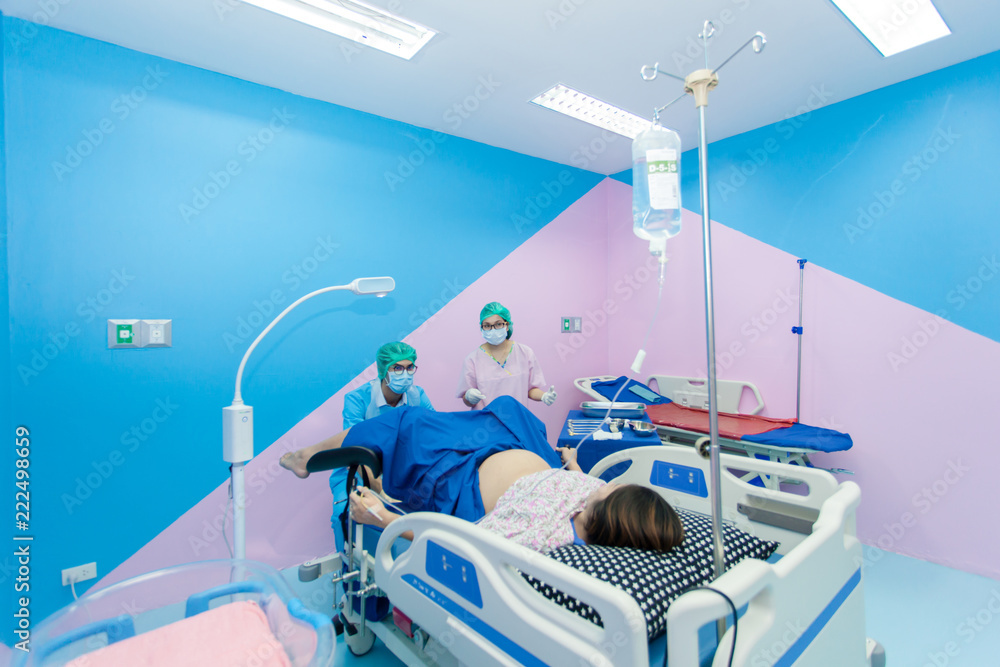 Maternity ward,obstetrician and nurse to the patient lying on a bed in ...