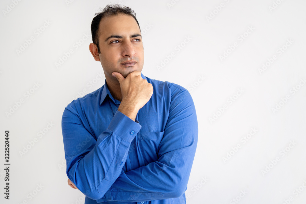 Pensive Indian man touching chin and looking away. Handsome guy ...