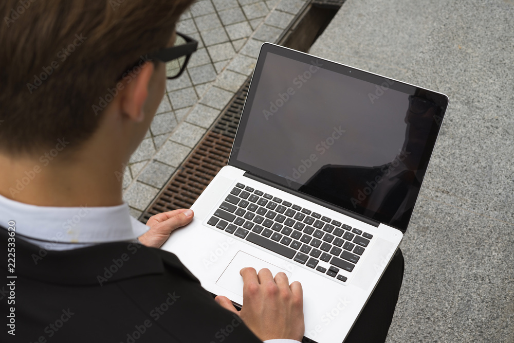 Young man working on street. A young college student sitting outside ...