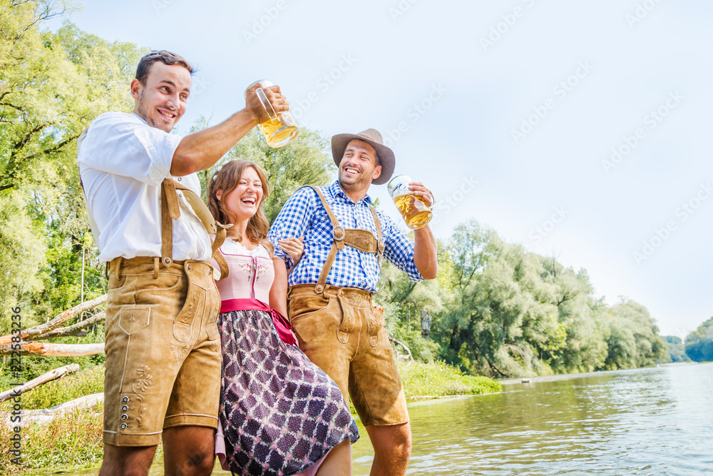 Oktoberfest Freunde in Lederhosen und Dirndl trinken Bier an der Isar ...