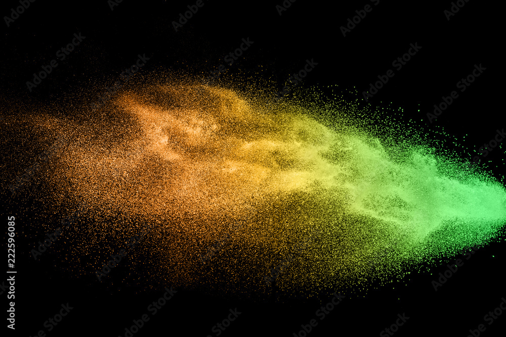 Green orange dust particles explosion on black background. Color powder ...