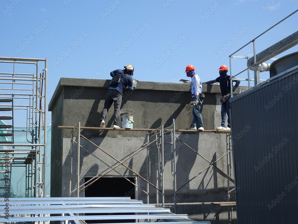 Brick wall plastered by construction workers using the cement plaster ...