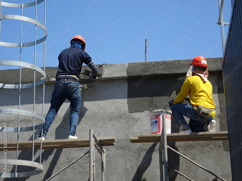 Foto de Brick wall plastered by construction workers using the cement ...