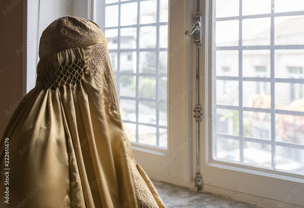 Indoor head and shoulder shot of a person wearing a gold-coloured Burqa ...