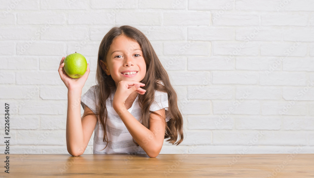 Young hispanic kid sitting on the table eating fresh green apple with a ...